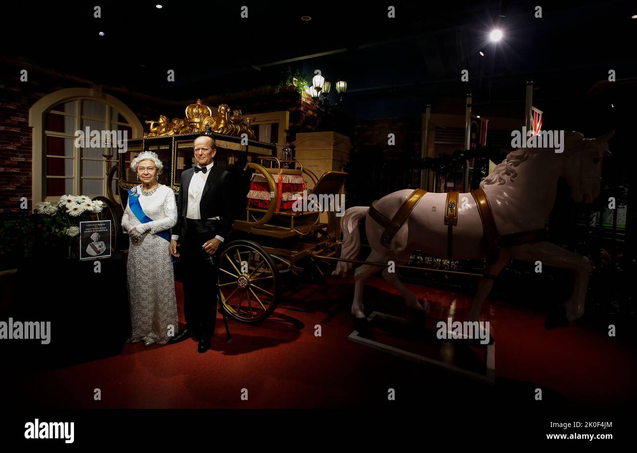Flowers and a tribute are set next to wax figures depicting the late ...
