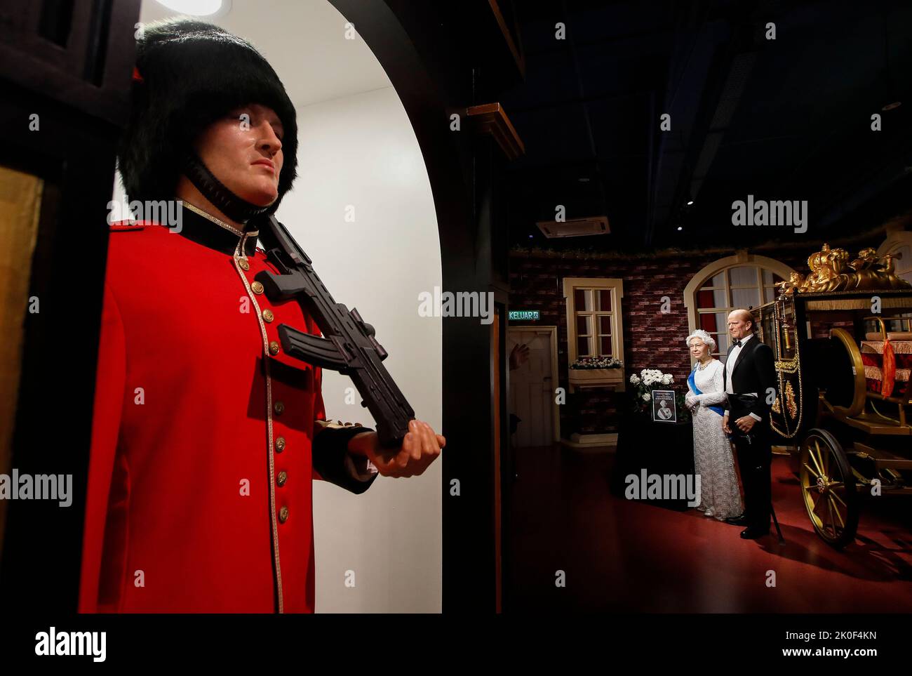 Flowers and a tribute are set next to wax figures depicting the late ...