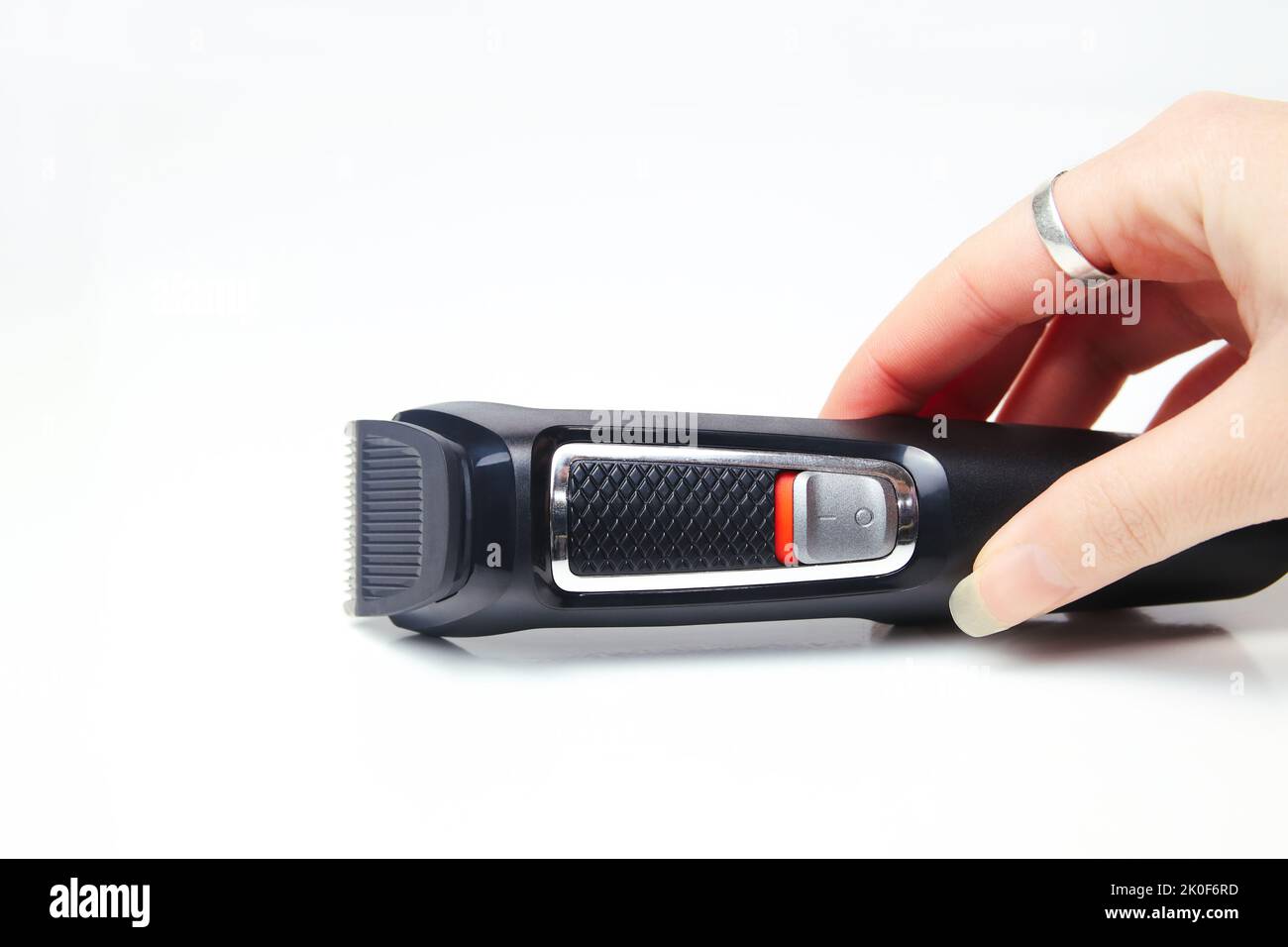 Defocus female hand holding electric clipper on white background ...