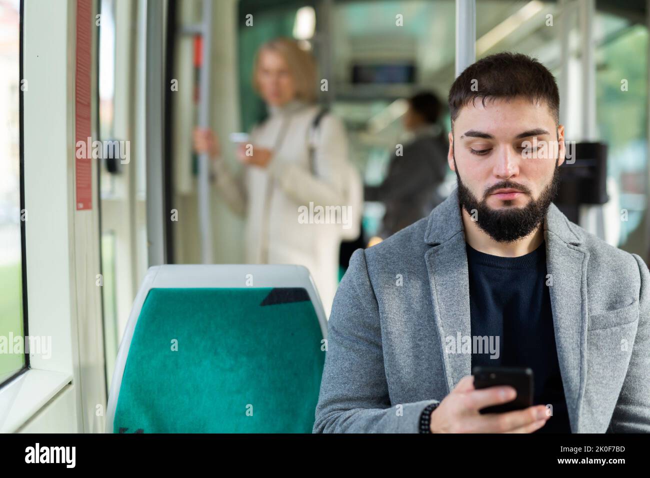Young man with phone in city bus Stock Photo - Alamy