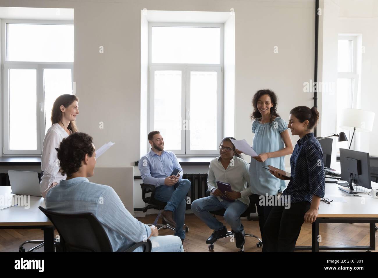 Happy office friends chatting in office, discussing success Stock Photo ...