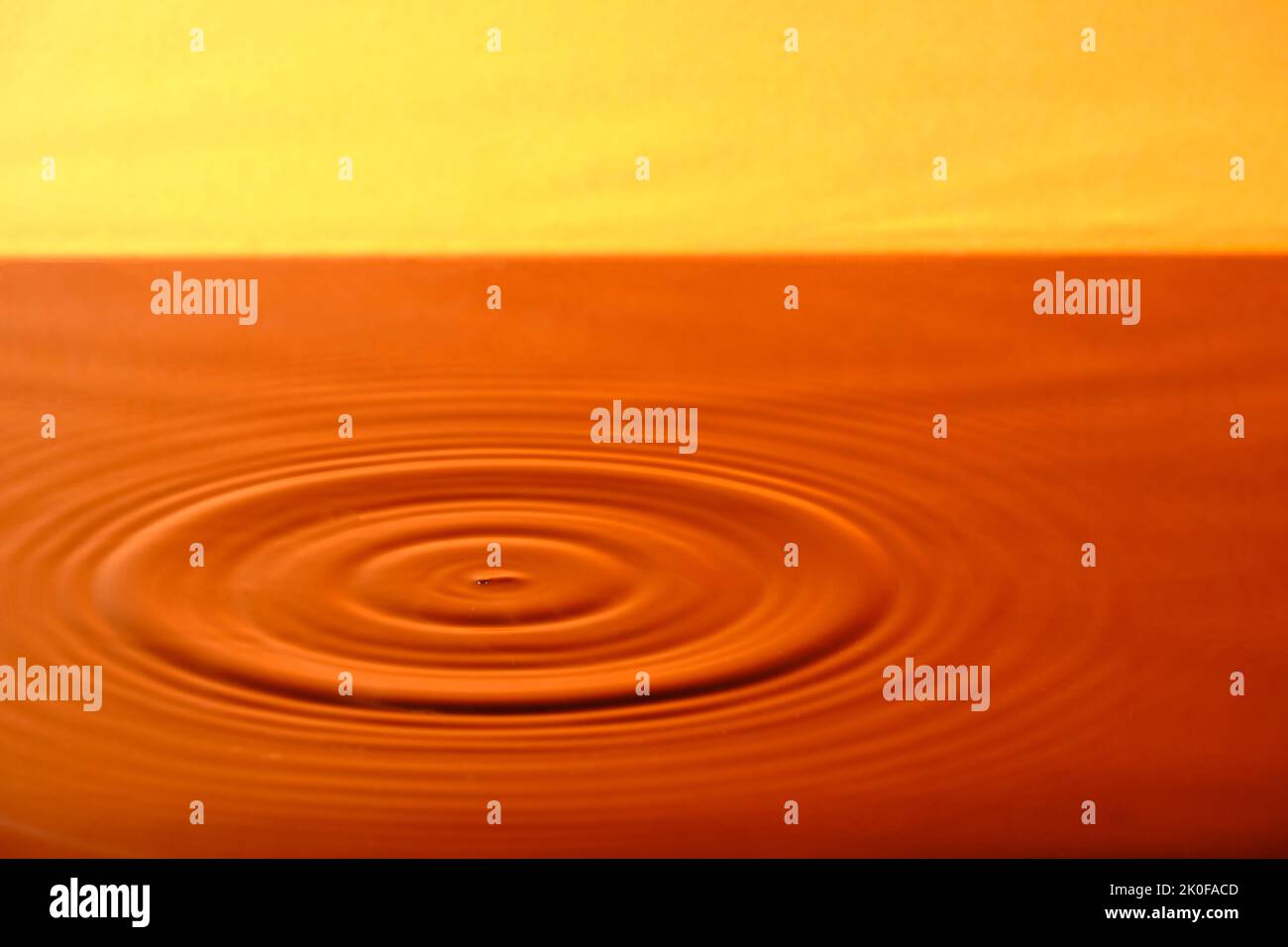 Splash drop of water with diverging water circles, on orange background ...