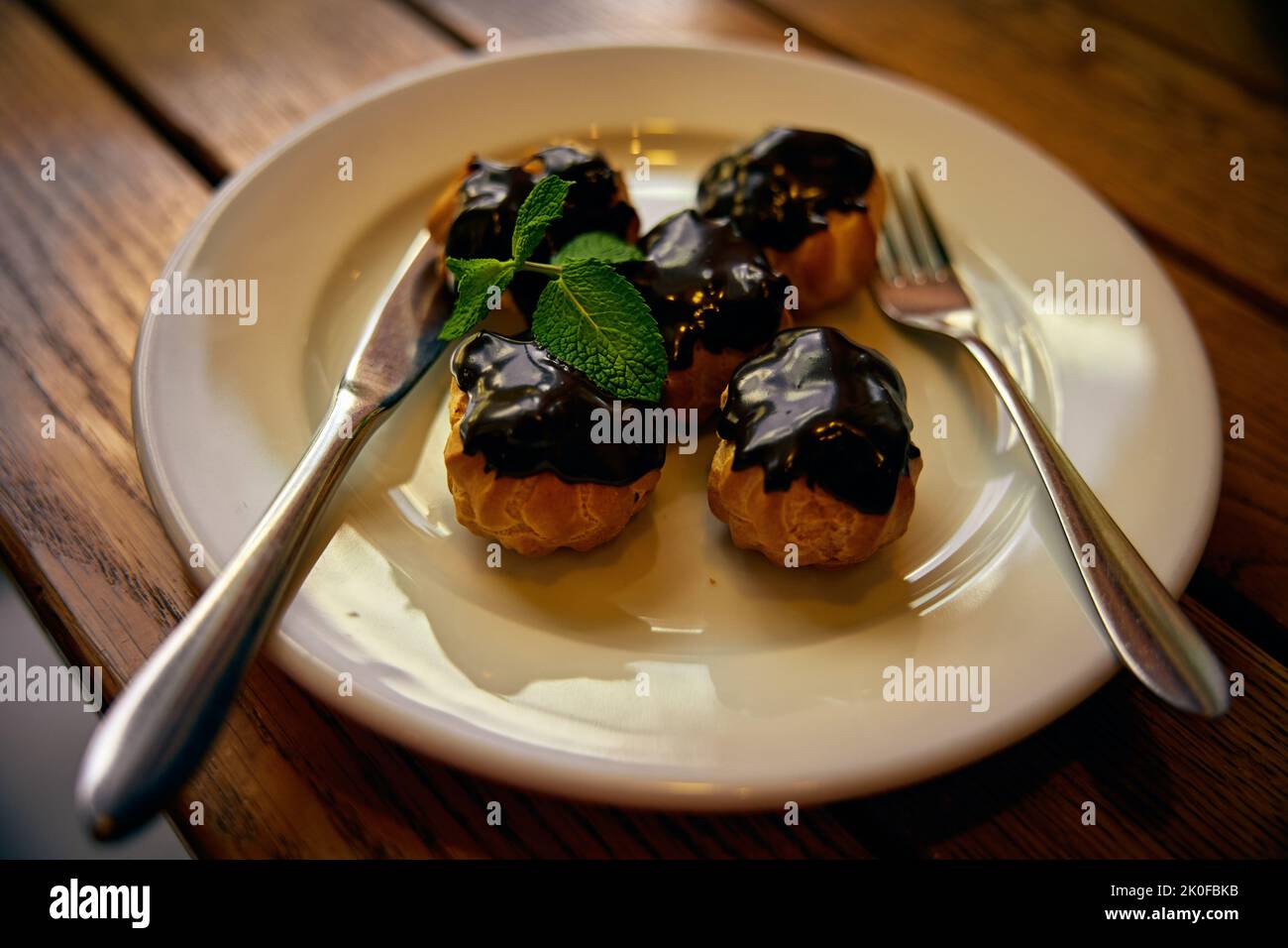 Several profiteroles with garnished with mint leaves on a white ceramic ...