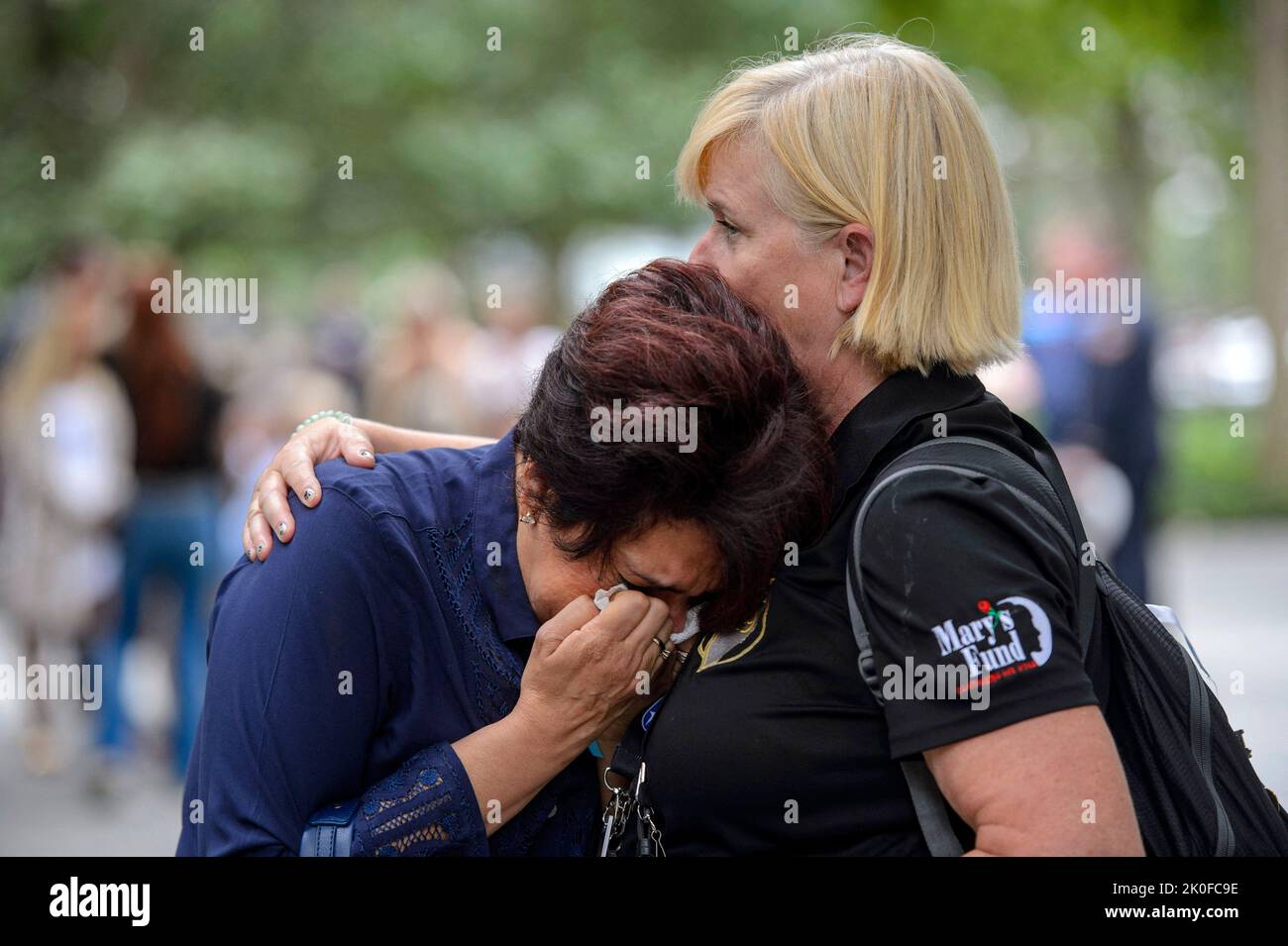 A crying woman is comforted during a ceremony to commemorate the ...