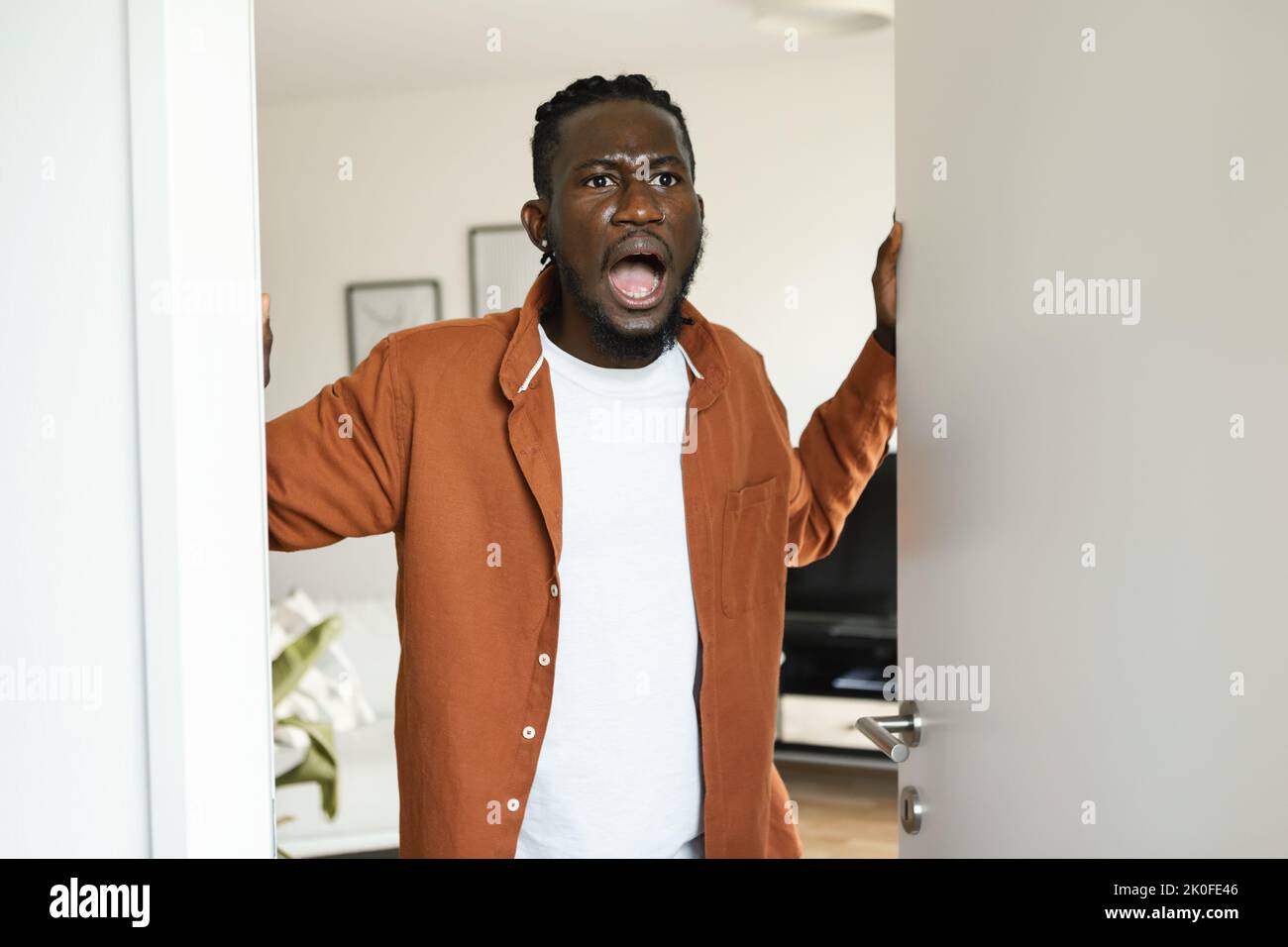 Shocked angry black man opening door, looking at something shocking and ...