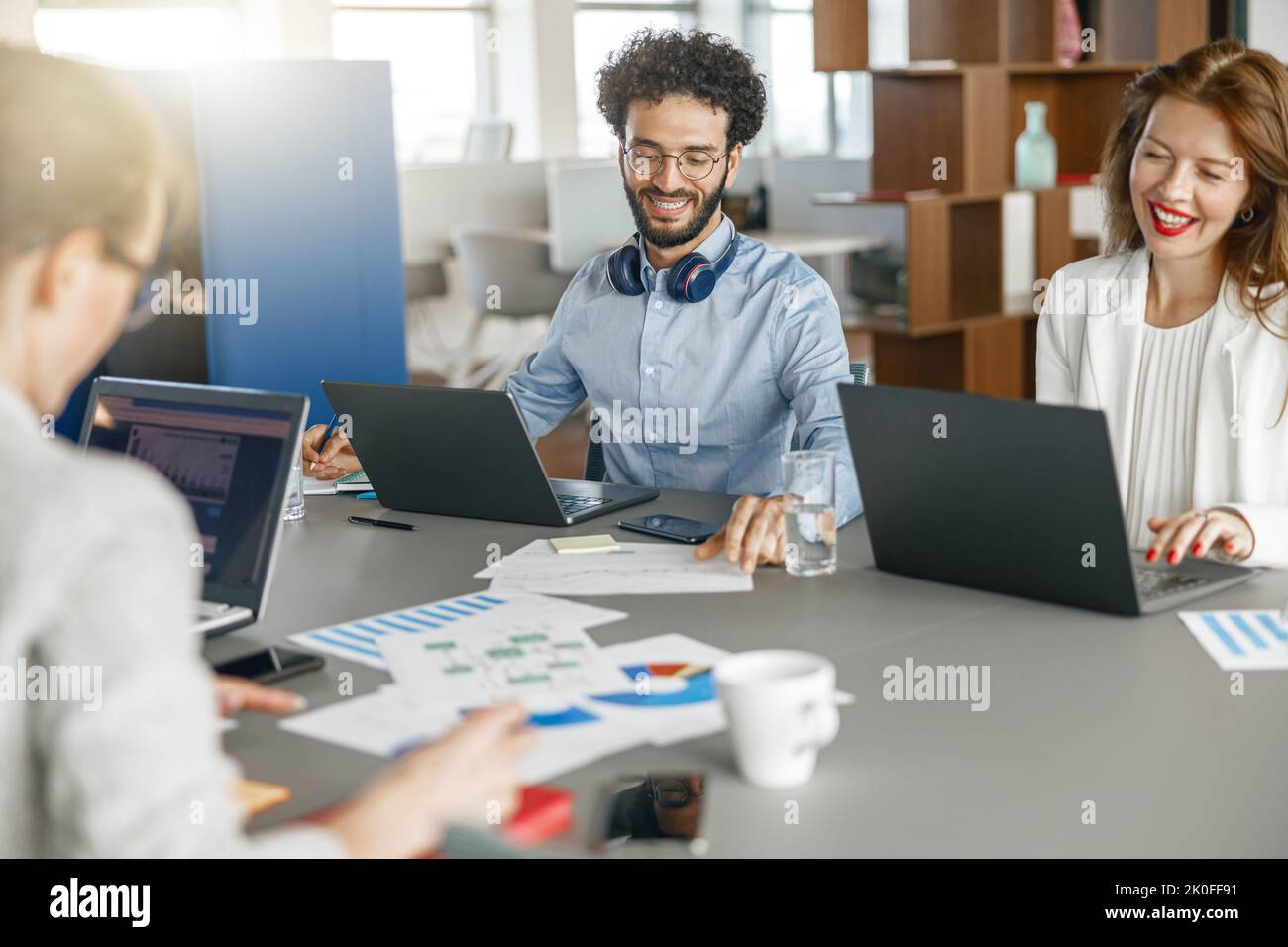 Group of happy diverse coworkers analyzing sales report while working ...