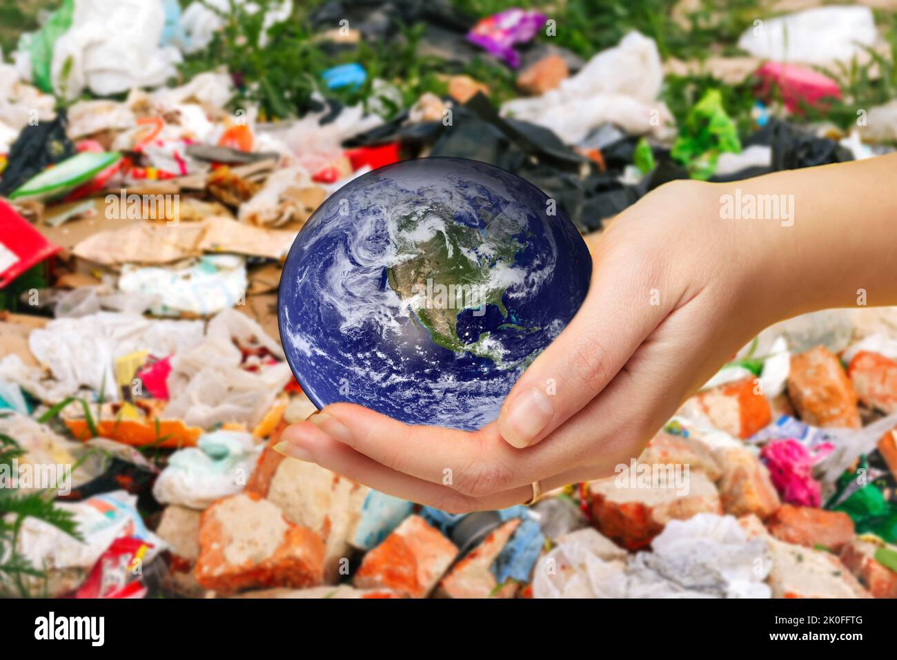 Defocus female hand holding planet globe on garbage background ...
