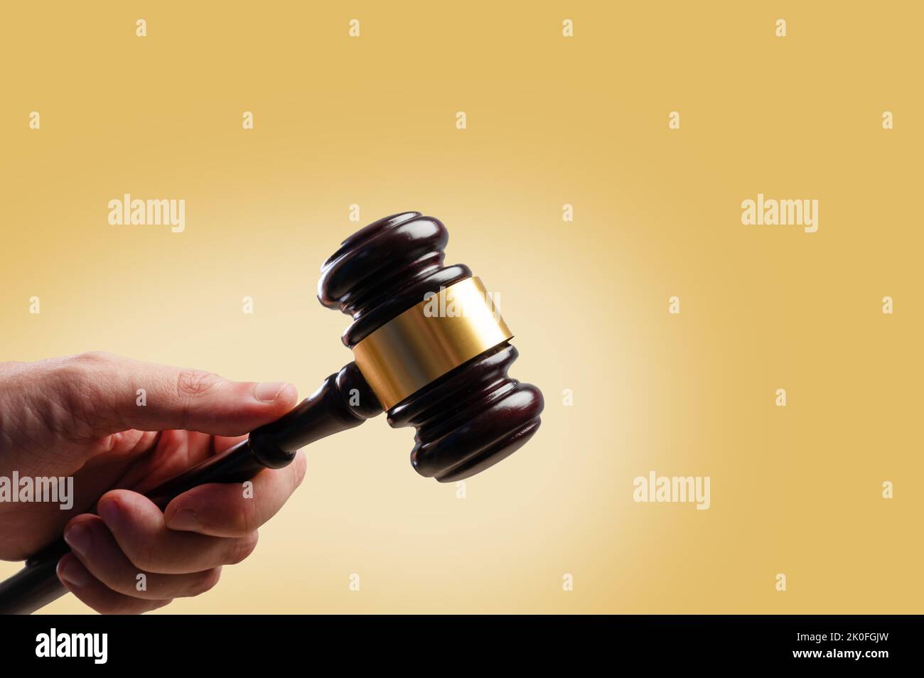 Wooden judge's gavel in a man's hand on a beige background. Symbol of ...