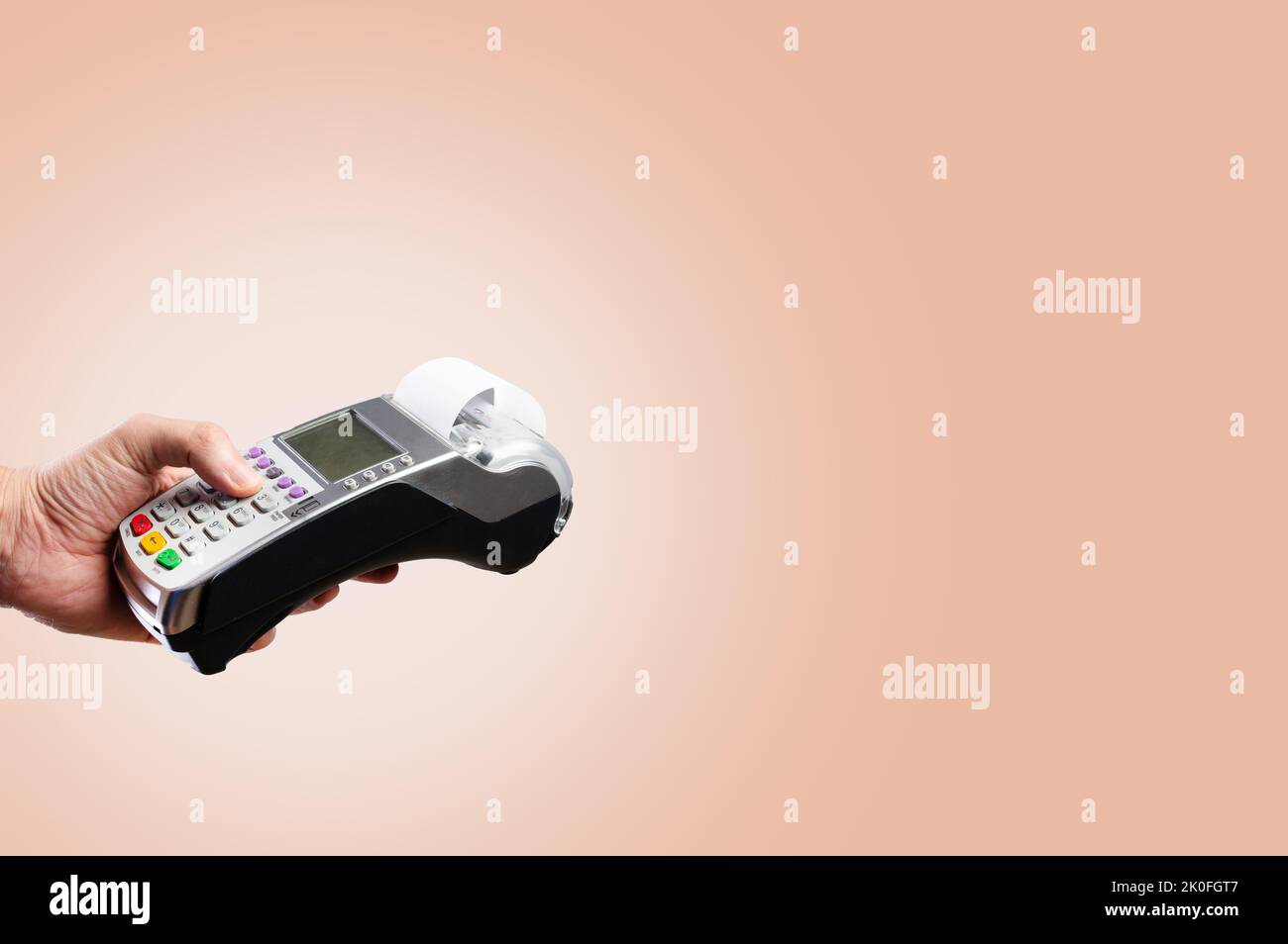 Cash terminal in a person's hand on a light beige background ...