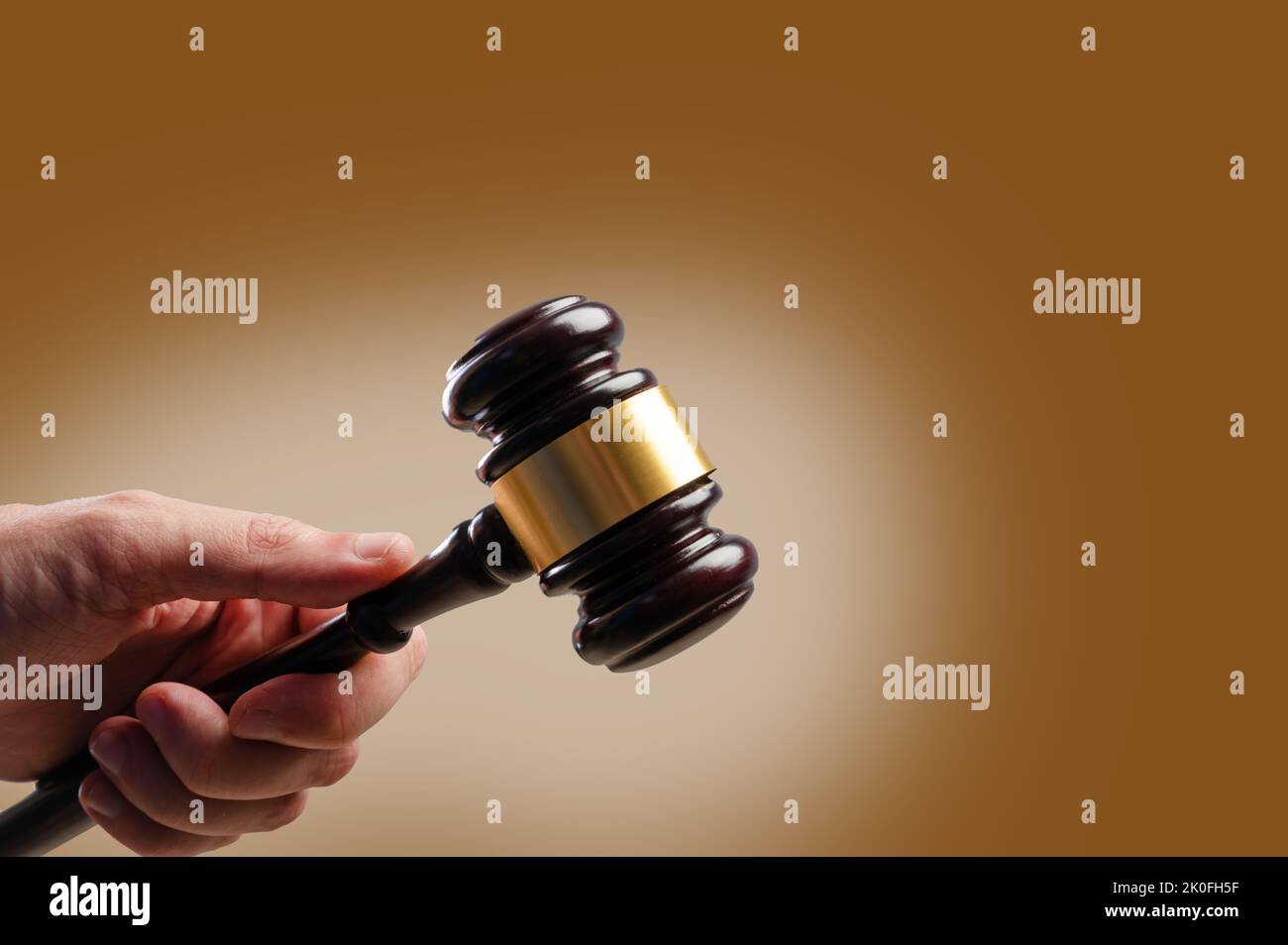 On a beige background, a wooden judge's gavel in a man's hand. Court ...