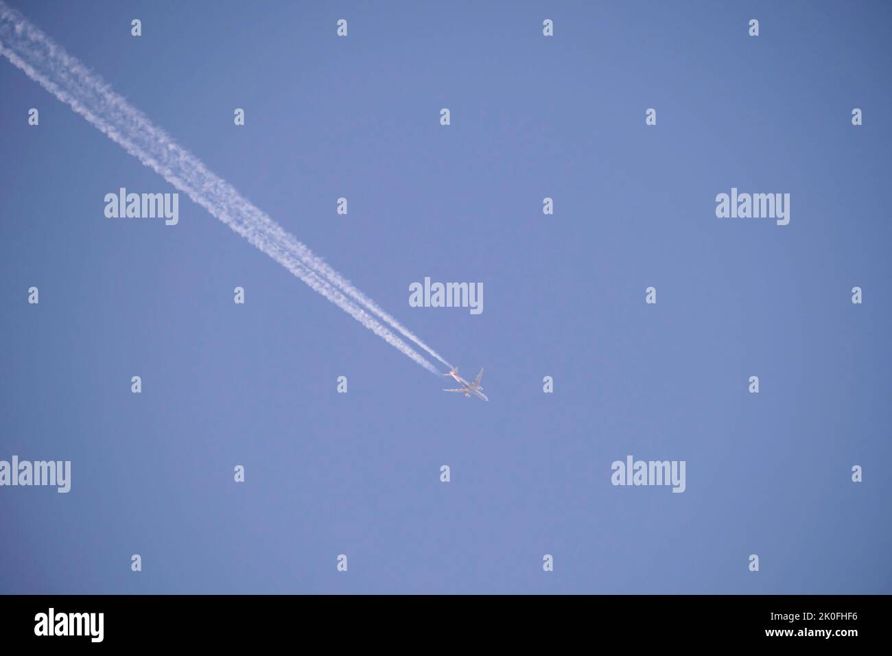 Distant passenger jet plane flying on high altitude on clear blue sky ...