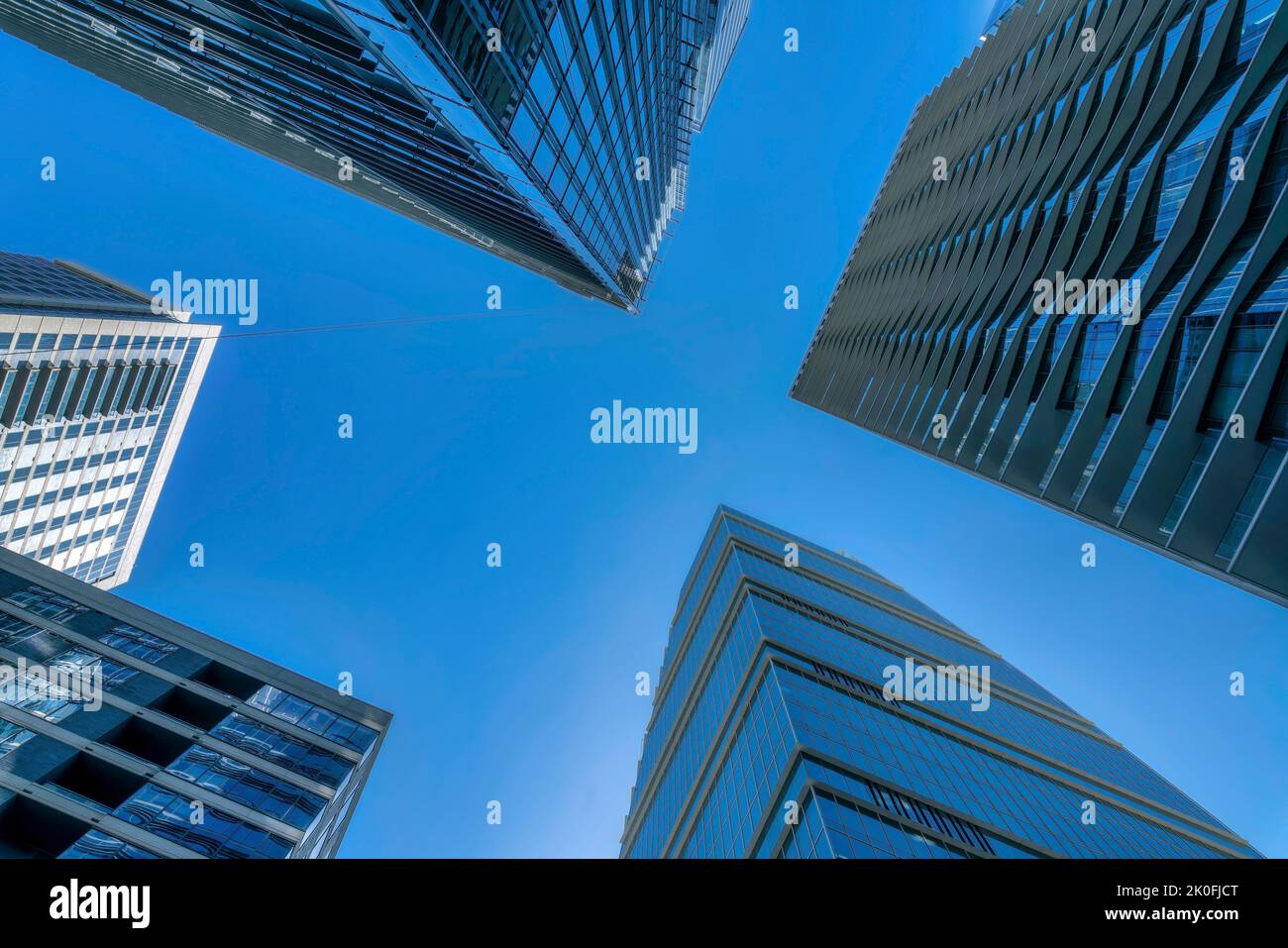 Looking up at the cloudless blue sky with towering skyscrapers ...