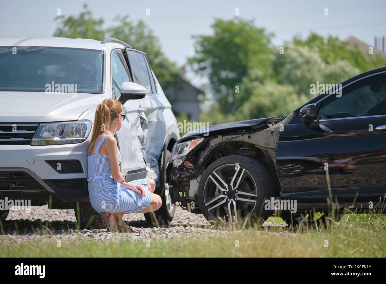 Sad female driver sitting on street side shocked after car accident ...
