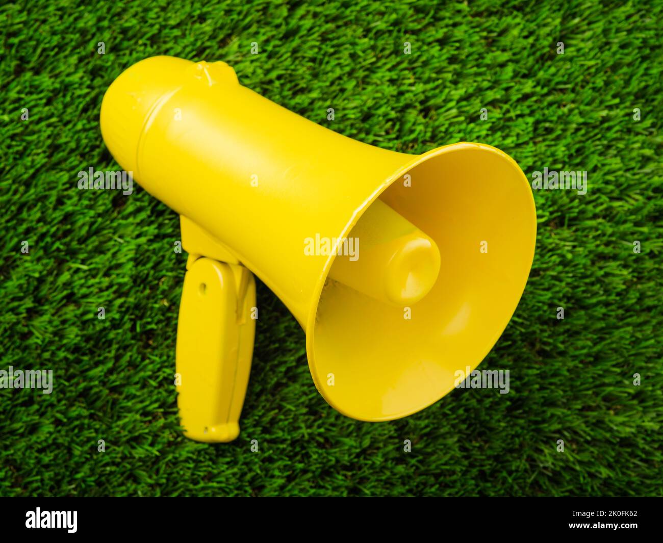 Close-up. Yellow megaphone on a green lawn. Symbol of false information ...