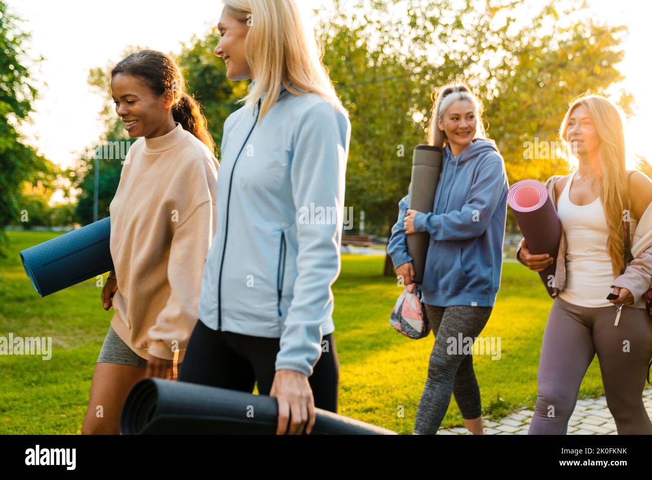 Multiracial women talking and smiling after yoga practice in summer ...