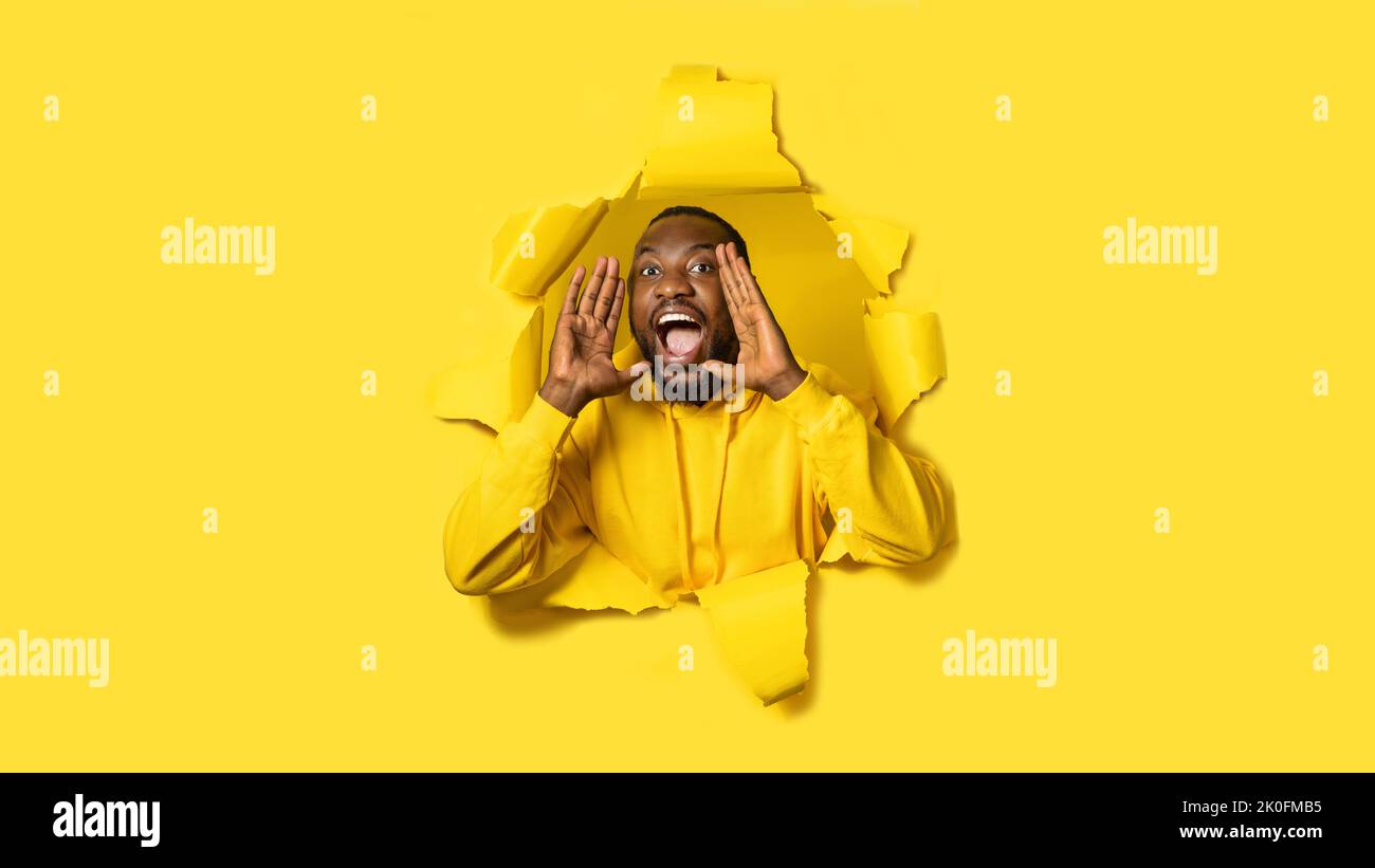 Astonished shouting. Emotional black man in torn yellow paper ...