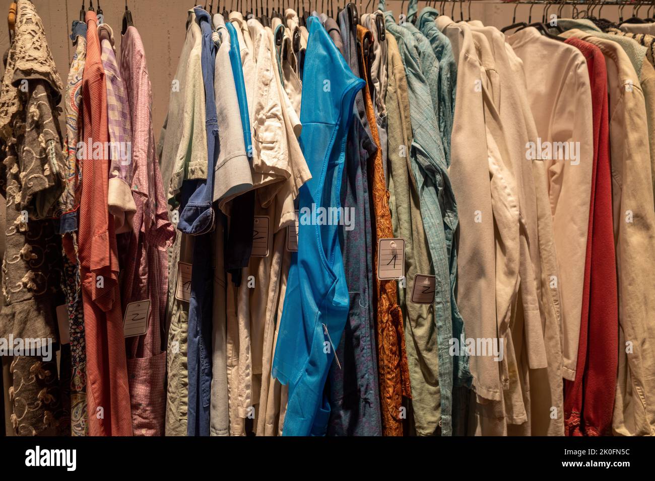 Row of colourful tone fabric and stylish shirts hang on aluminium ...
