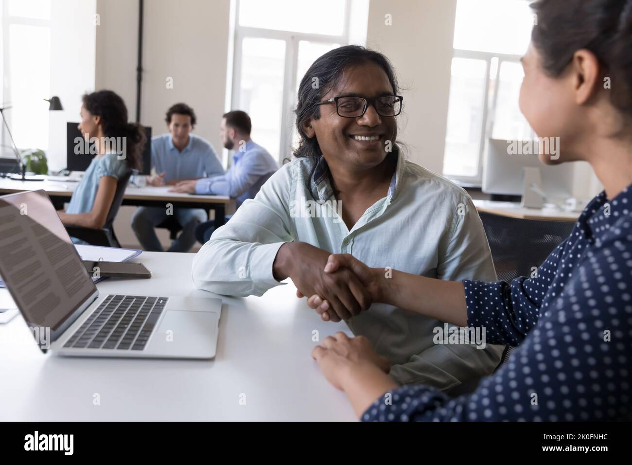 Happy Indian employees giving handshakes at shared workplace Stock ...