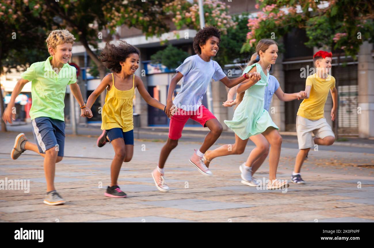 Happy tween friends running together on summer city street Stock Photo ...