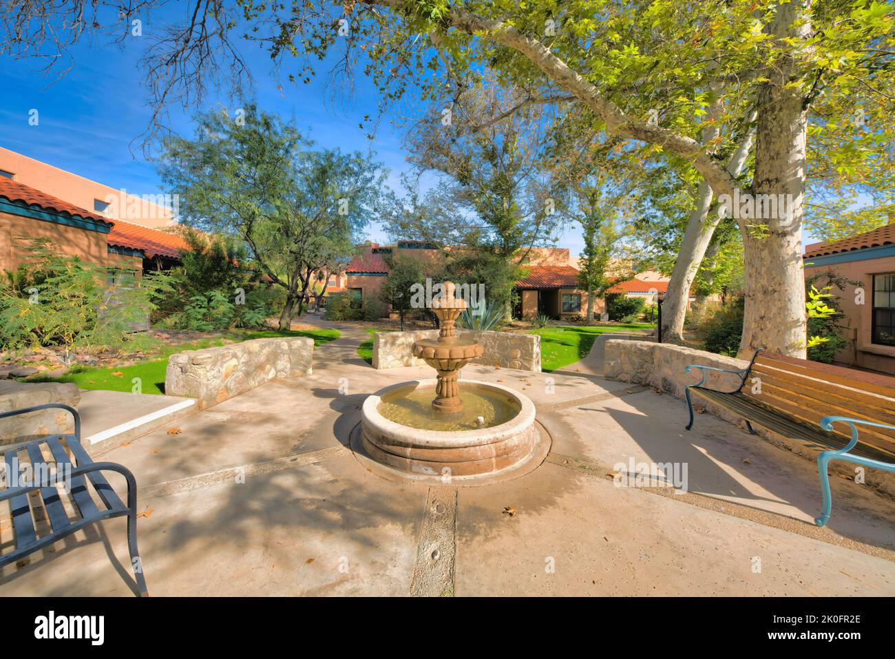 Metal and wood benches with fountain at the middle outside the ...