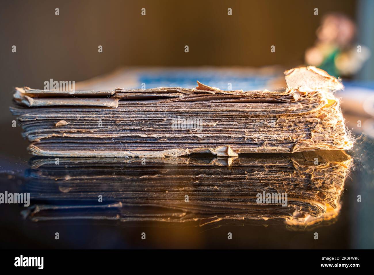 A thick large, ragged, old torn book on a transparent glass table ...
