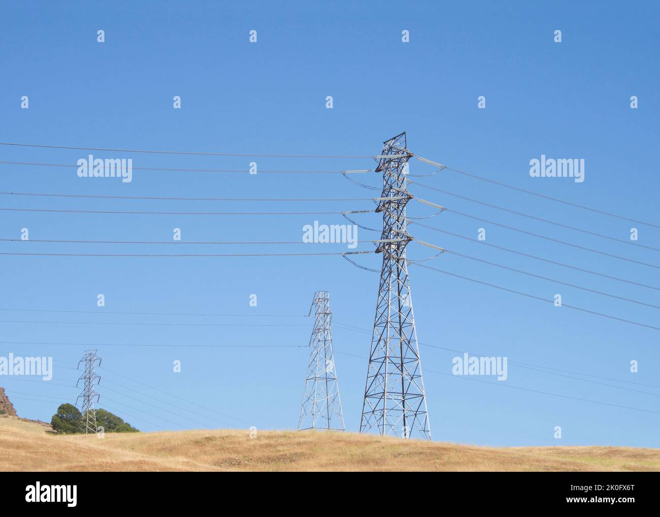 Metal power towers with power lines running through them on a hillside ...