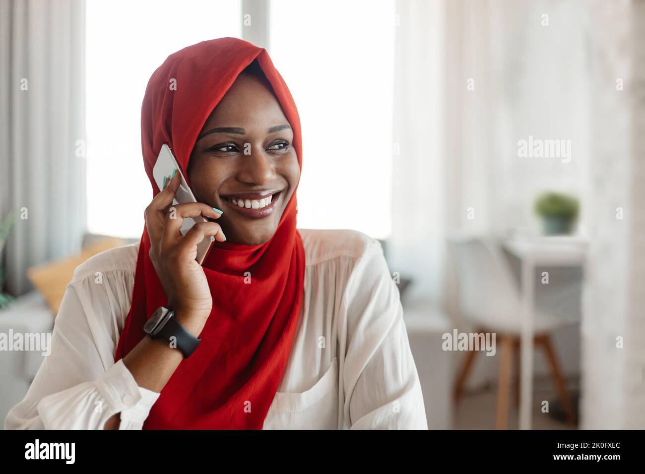 Positive black muslim lady in hijab making call on mobile phone ...