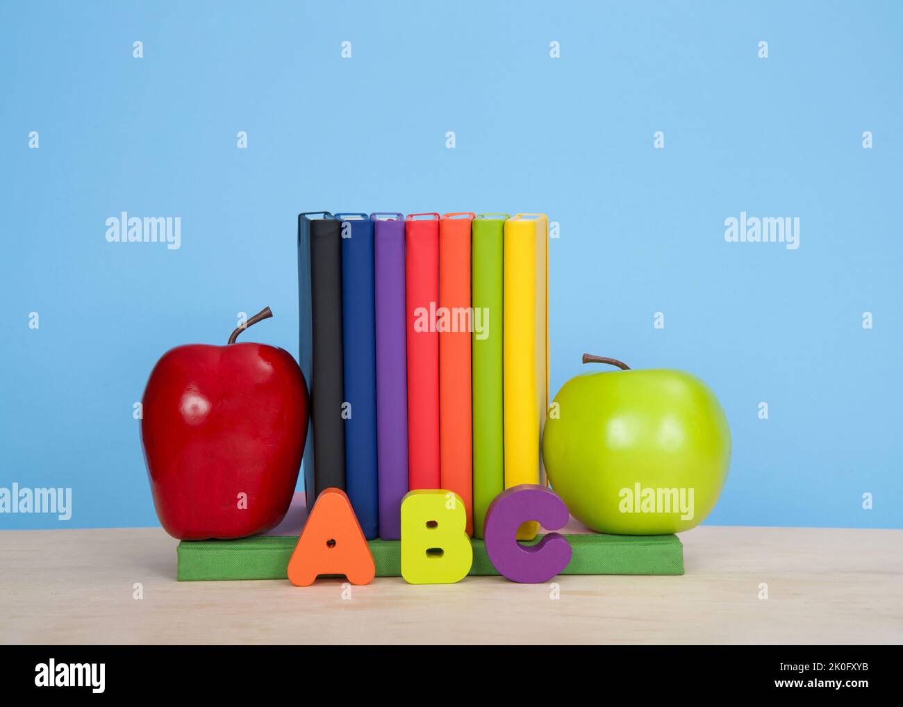 Close up of colorful books lined up in a row with red and green apples ...
