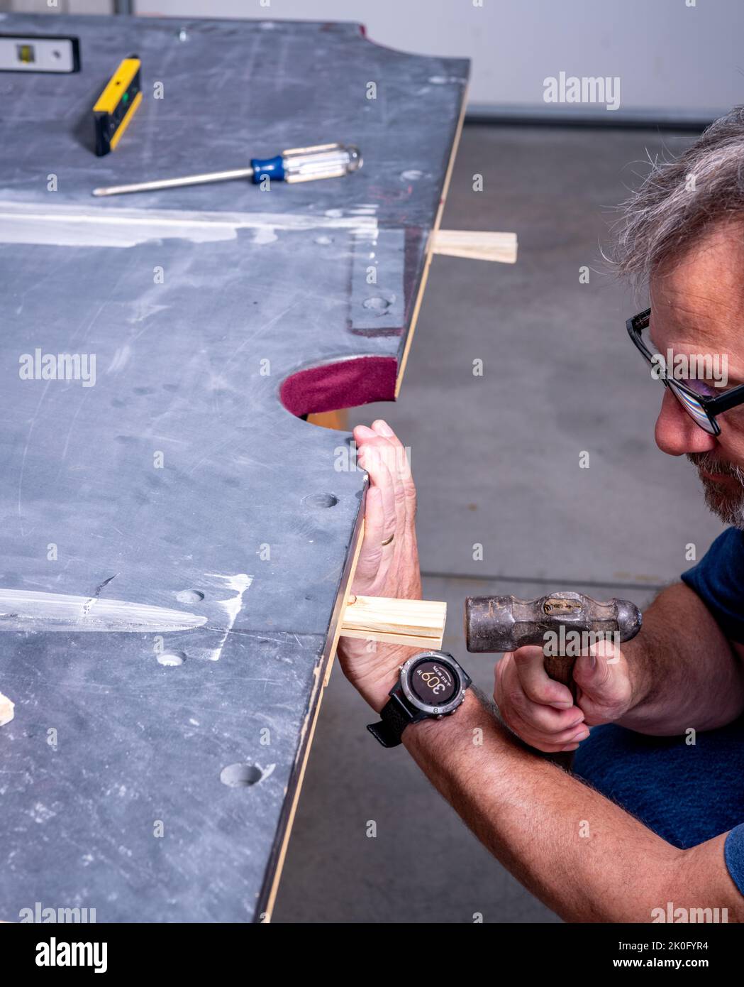 Professional installs a pool table using shims to help level Stock ...