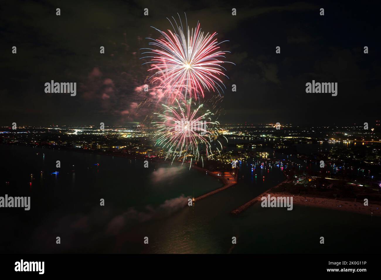 Aerial view of bright fireworks exploding with colorful lights over sea ...