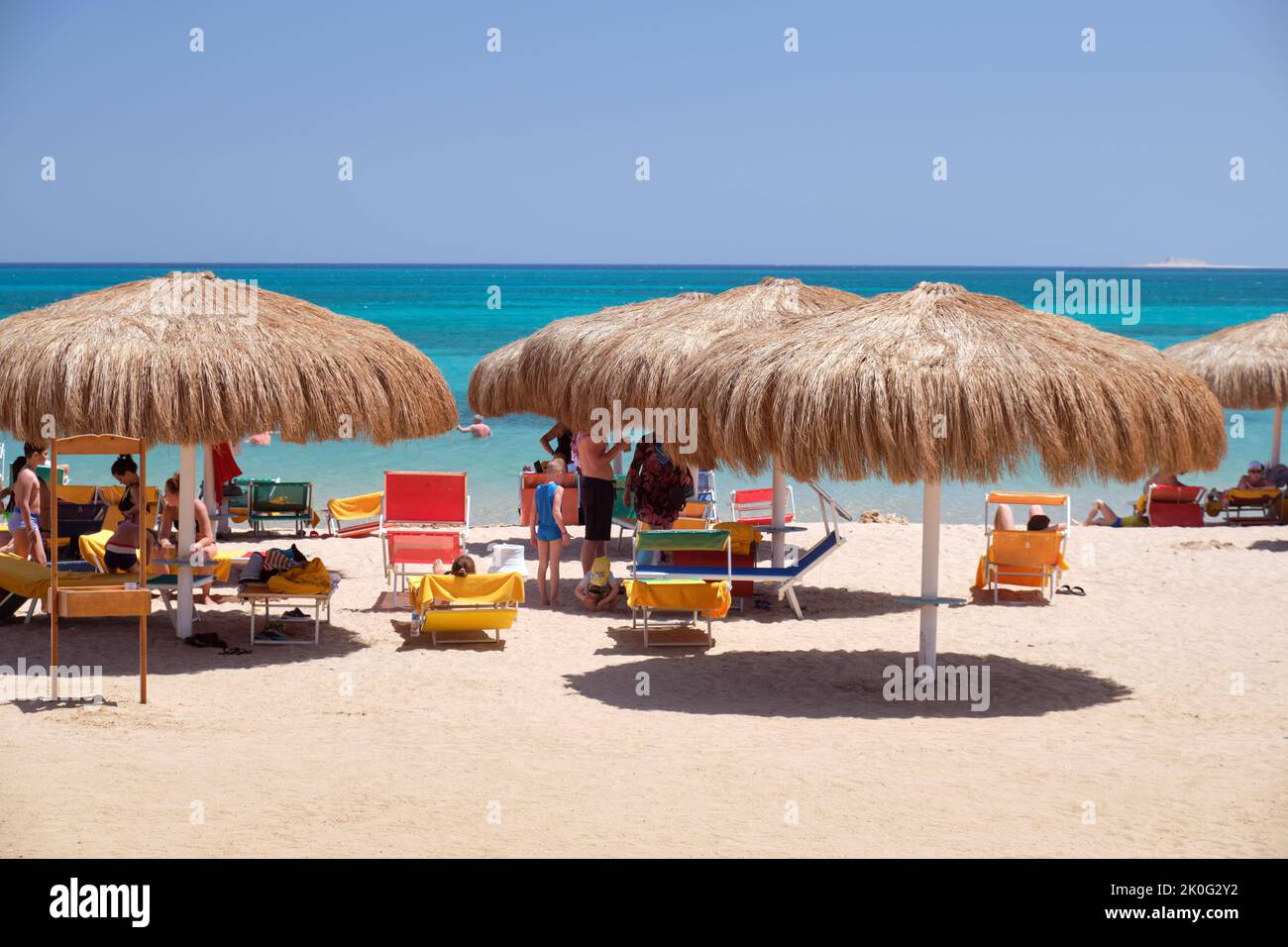 Straw shade umbrellas on sea tropical beach with resting sunbeds ...