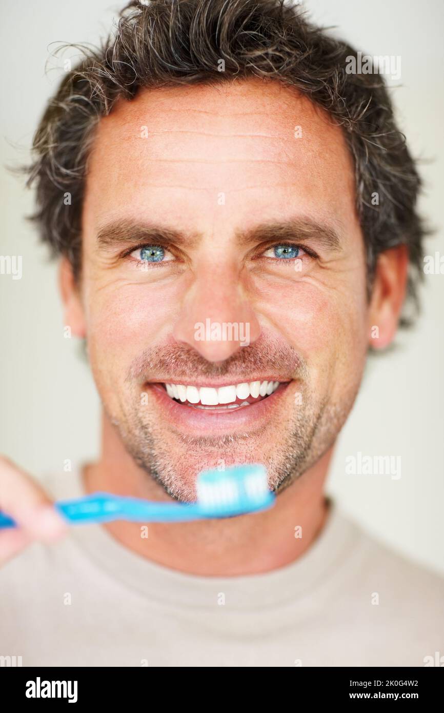 Man brushing teeth. Closeup of mature man holding toothbrush and ...