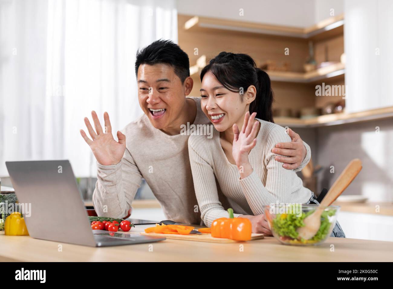 Loving asian spouses having video call while cooking at kitchen Stock ...