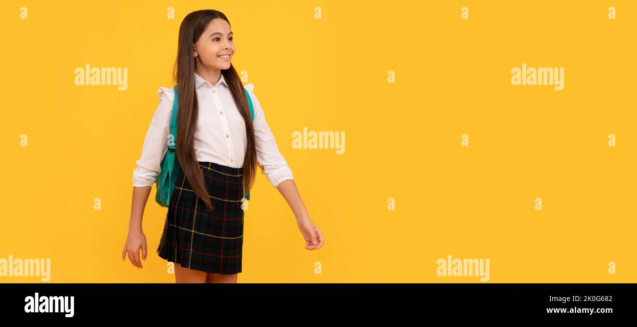 happy teen girl in school uniform full length on yellow background ...