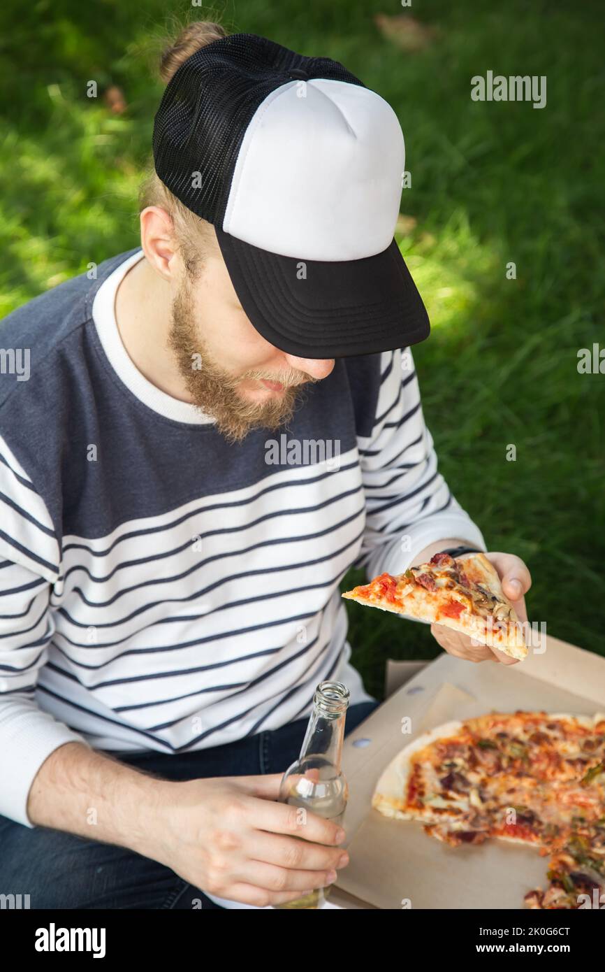 A young man eating pizza on a picnic Stock Photo - Alamy