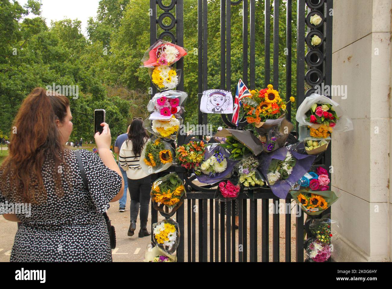 London, UK. 11th Sep, 2022. A woman takes photos of floral tributes at ...