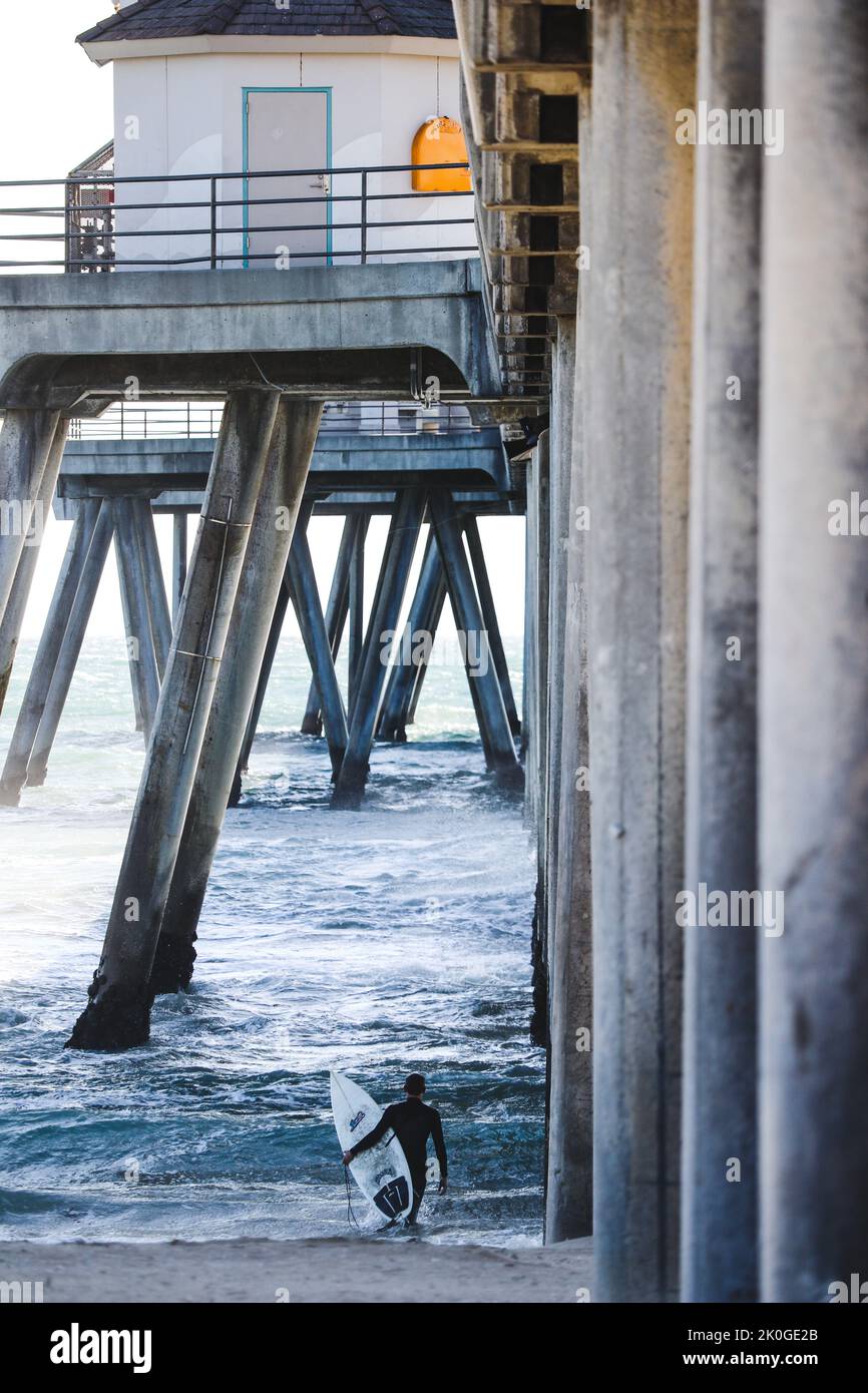 Surfer under the pier Stock Photo - Alamy