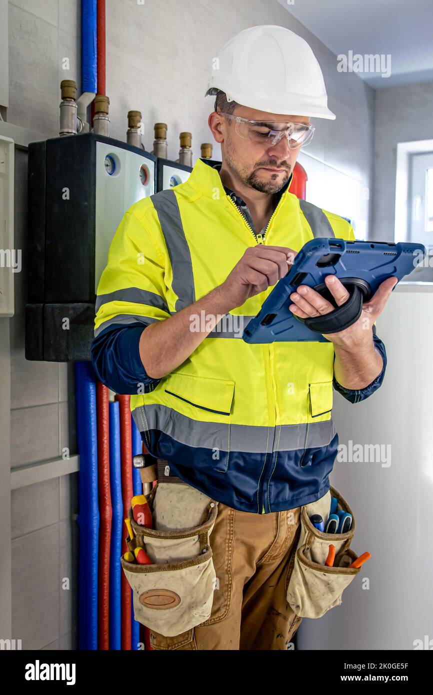 Man, an electrical technician working in a switchboard with fuses, uses a tablet Stock Photo - Alamy