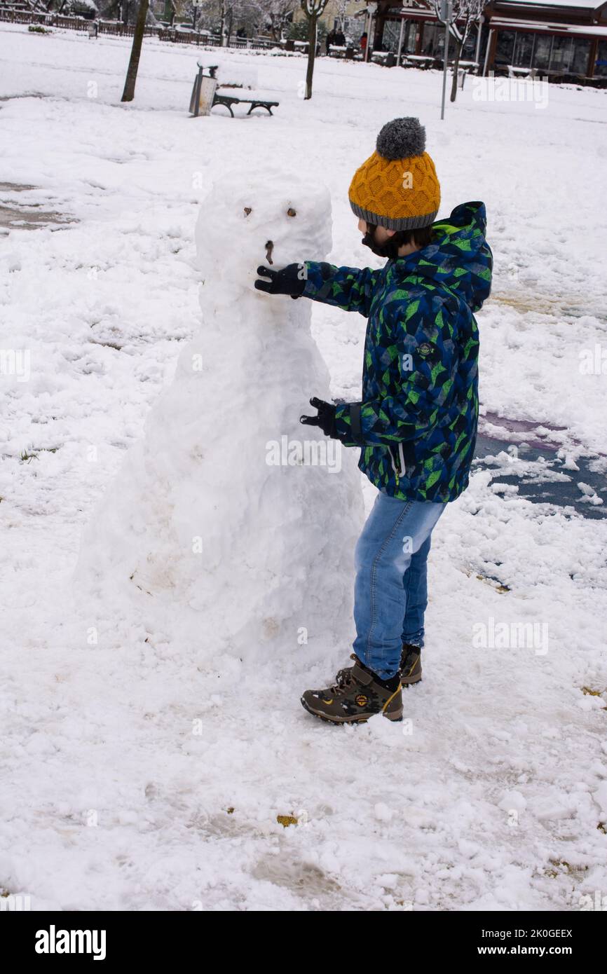 Cute boy making snowman in park on winter vacation Stock Photo - Alamy