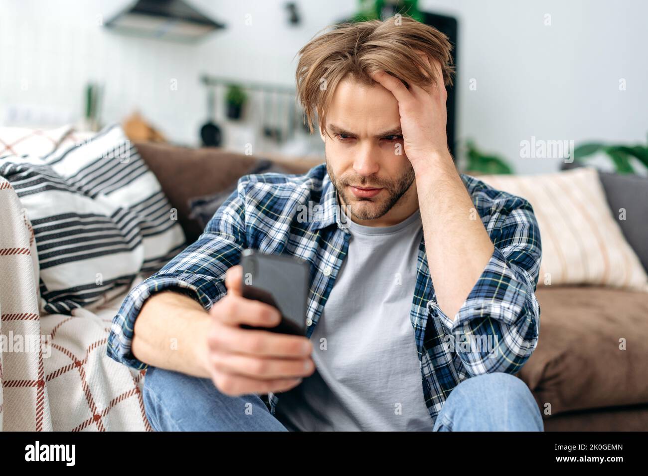 Frustrated unhappy caucasian young stylish man, sitting on a floor near ...