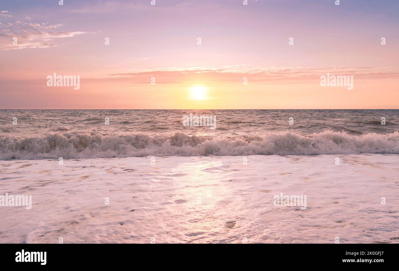 Sea splashing waves backlit by setting sun in front of beautiful sunset ...