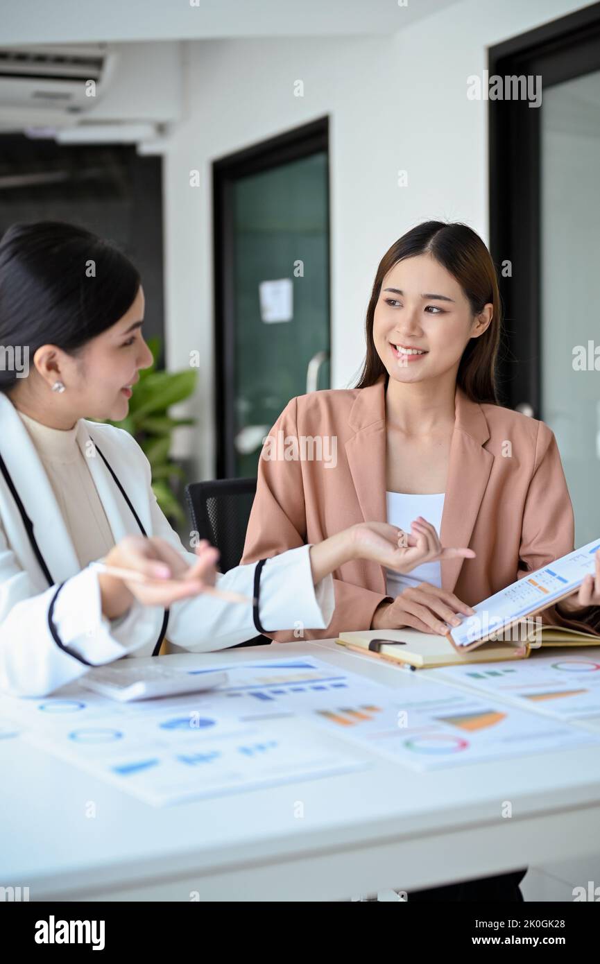 Two beautiful young Asian female office employees talking and ...