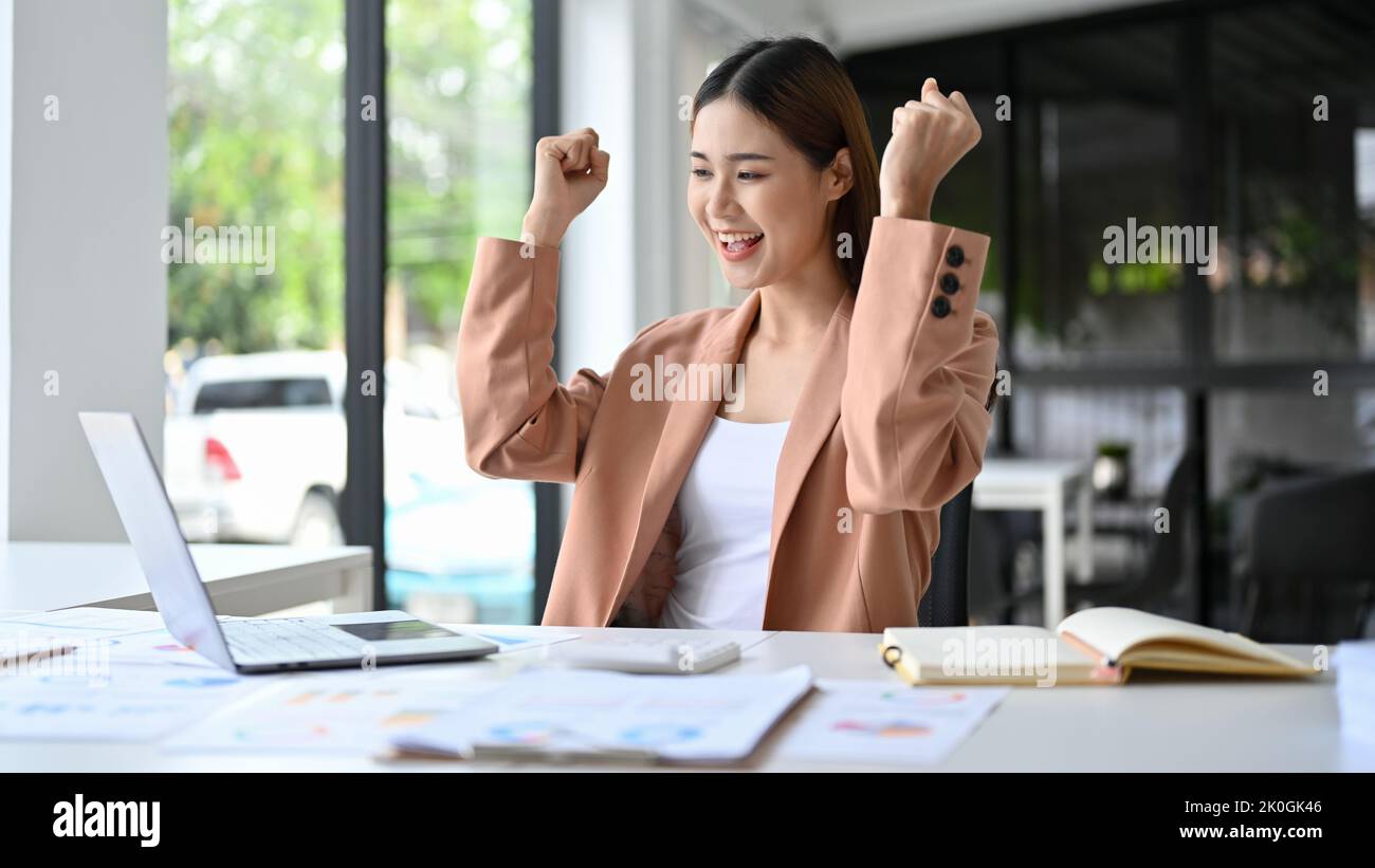 Attractive and successful Asian businesswoman celebrating at her office ...