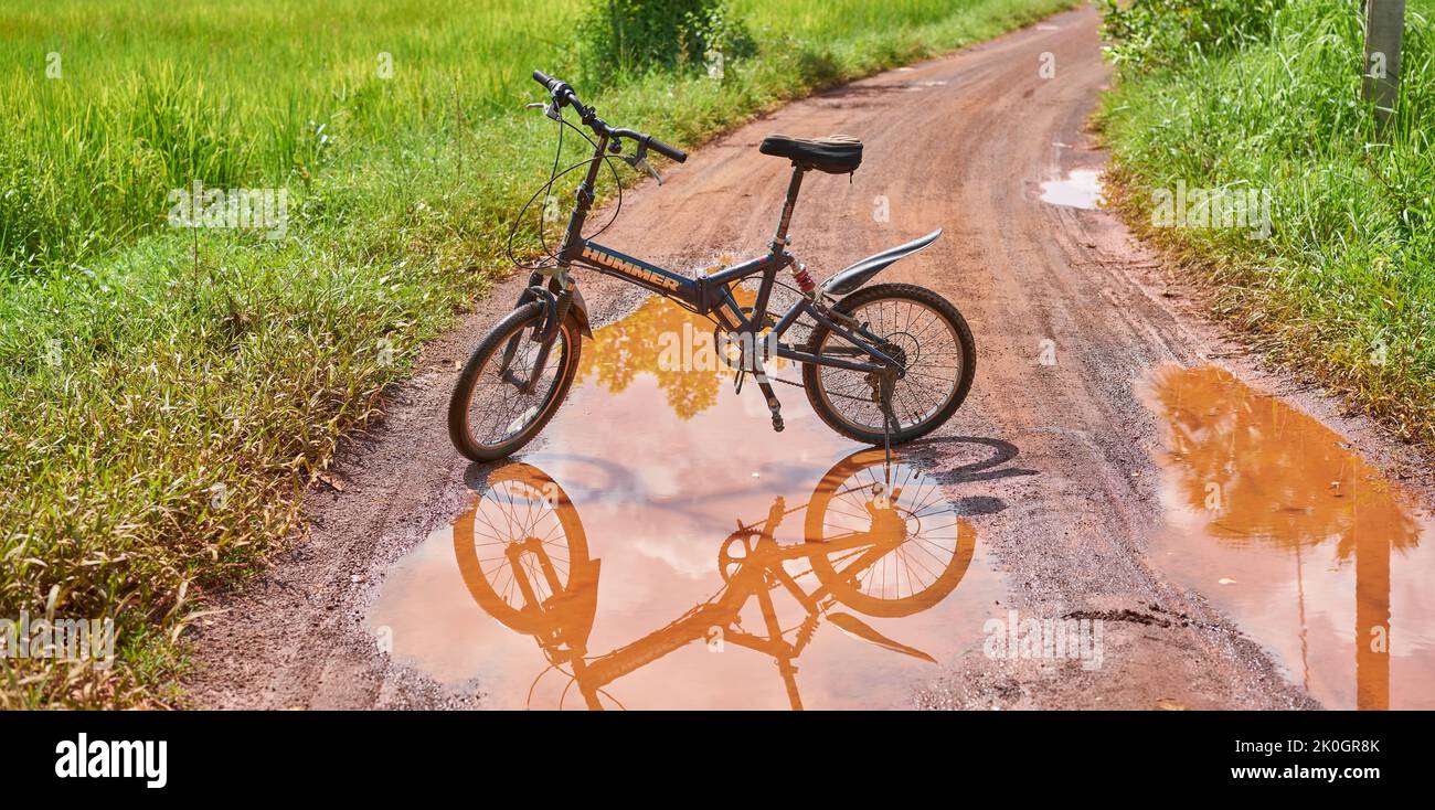 A mountain bicycle and reflection in a puddle of water on a country ...