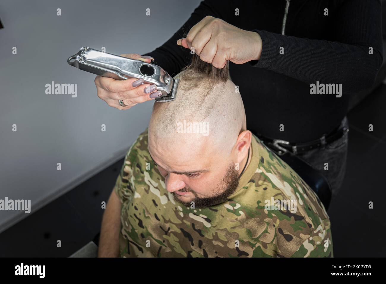 A young man in a military uniform shaves his head bald for military ...