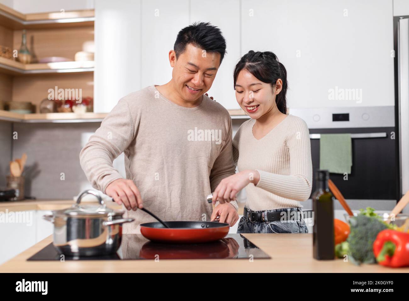 Happy chinese husband and wife making dinner together, kitchen interior ...
