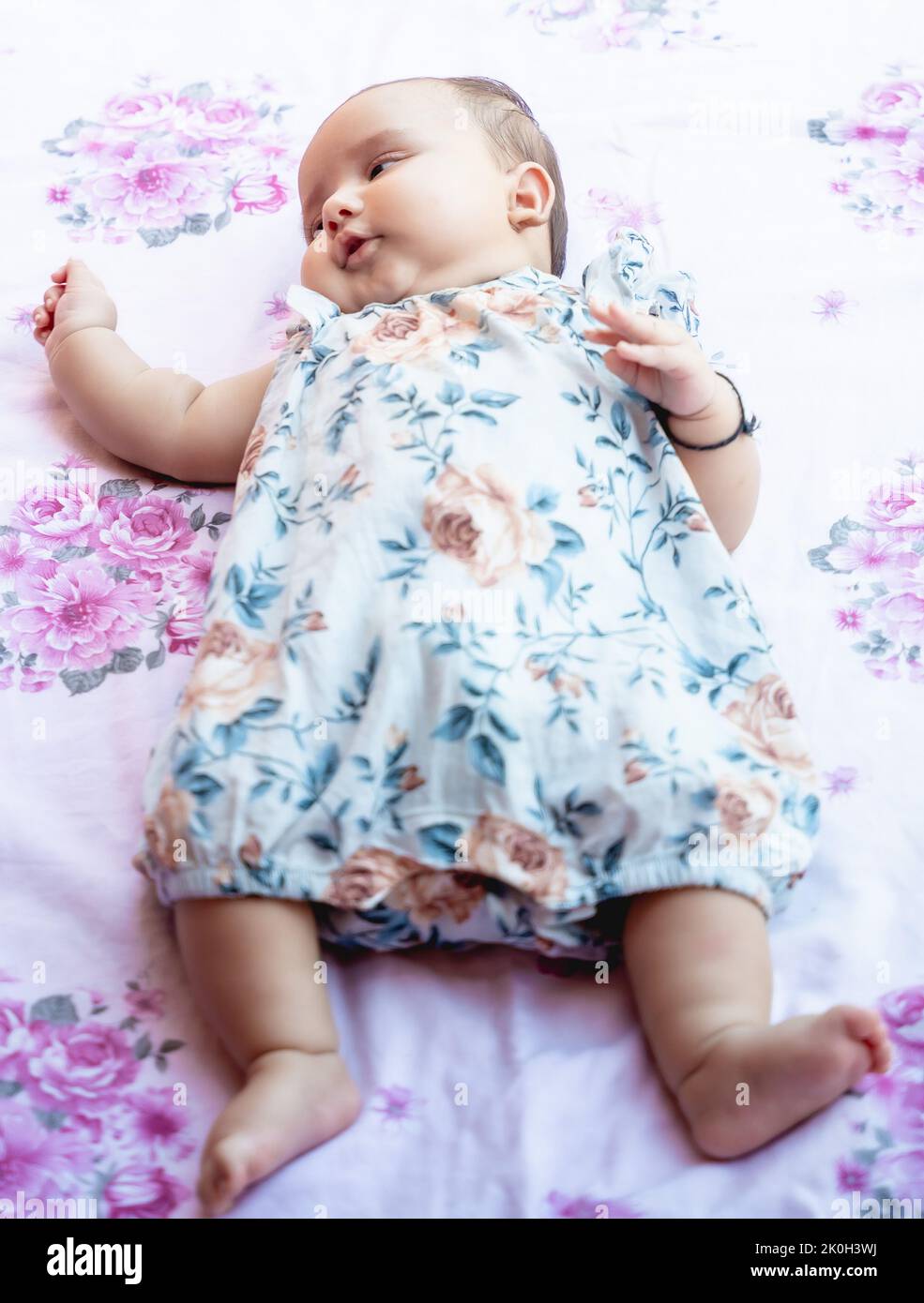 Cute baby girl lying down and looking in camera Stock Photo - Alamy