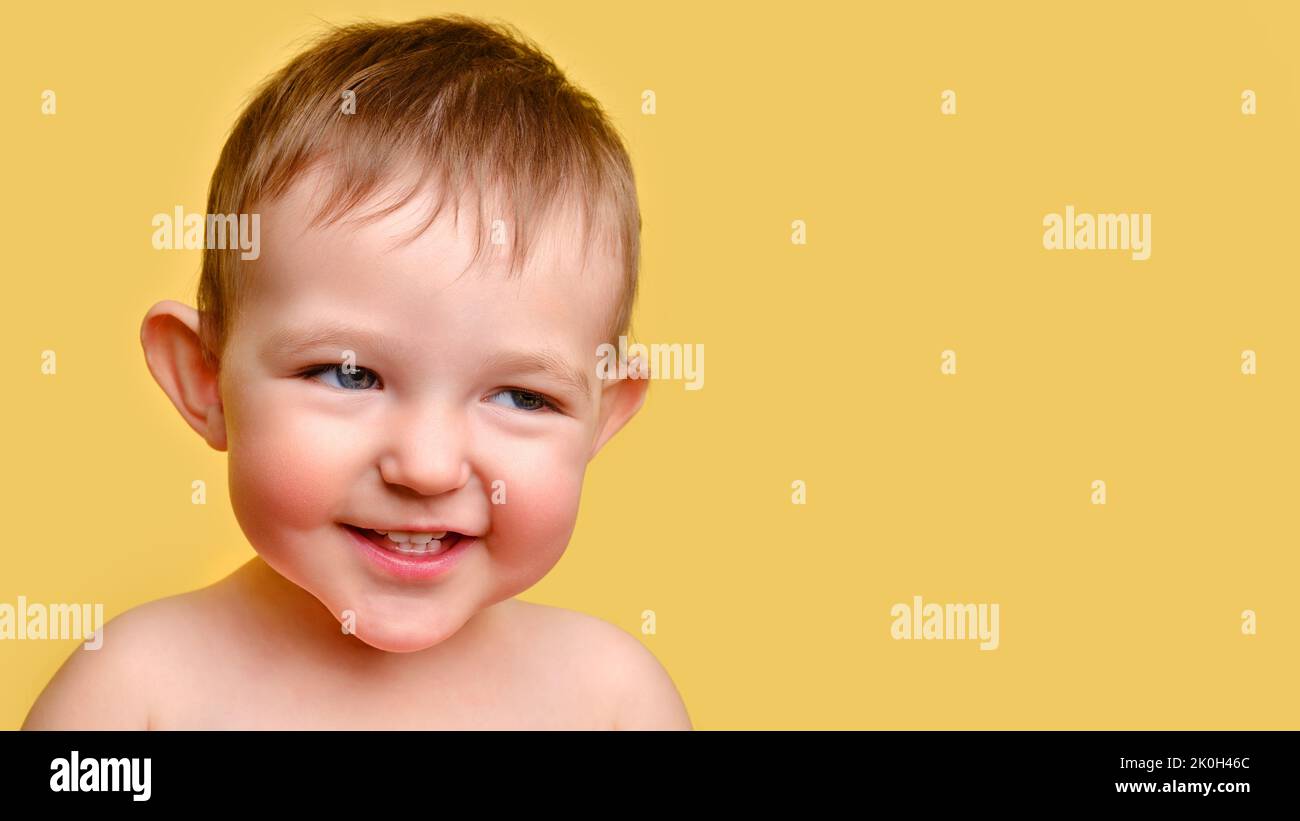 Sly toddler baby, studio yellow background, copy space. Portrait of an ...