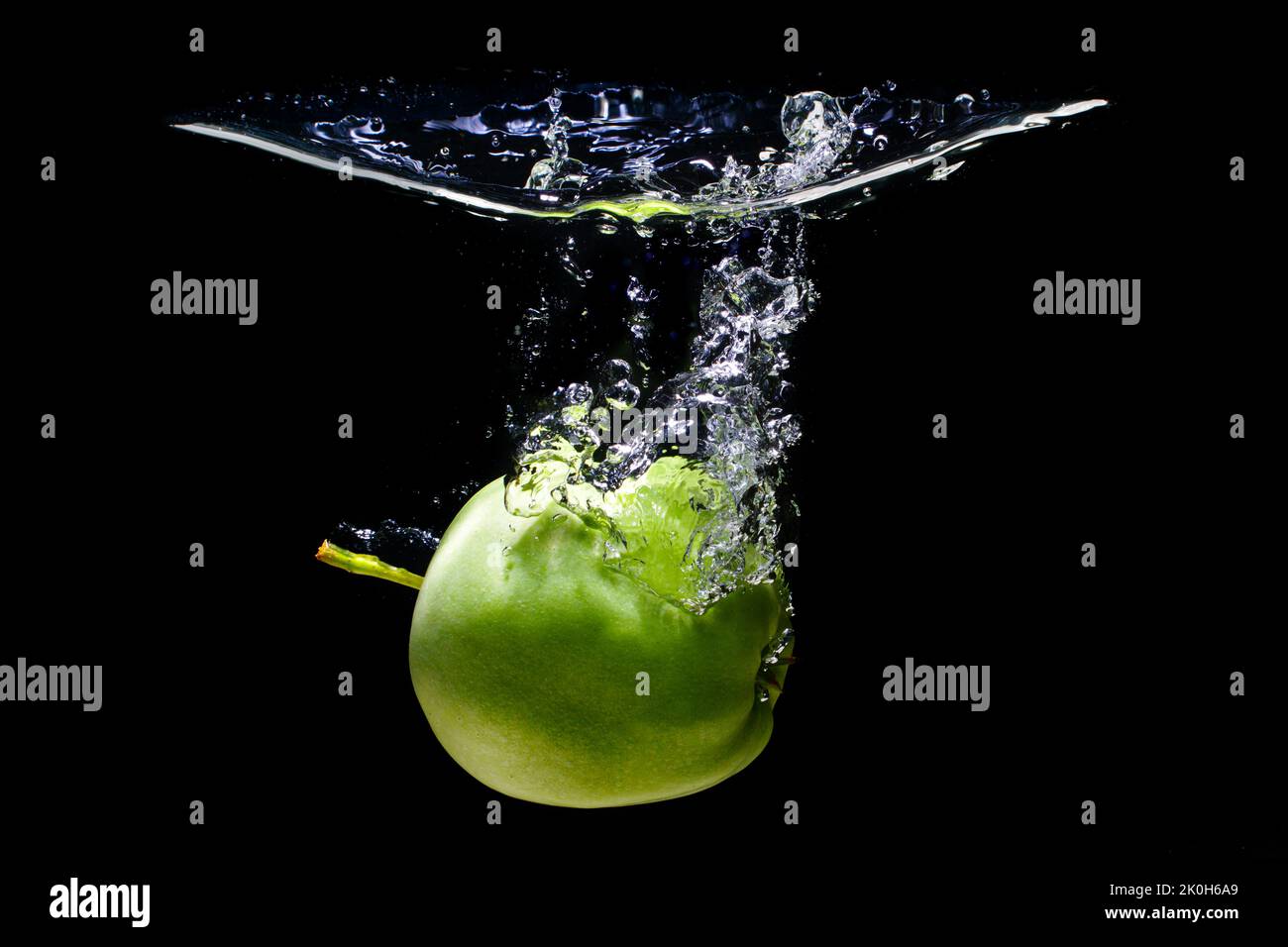 Green apple going underwater with splashes and bubbles on black ...