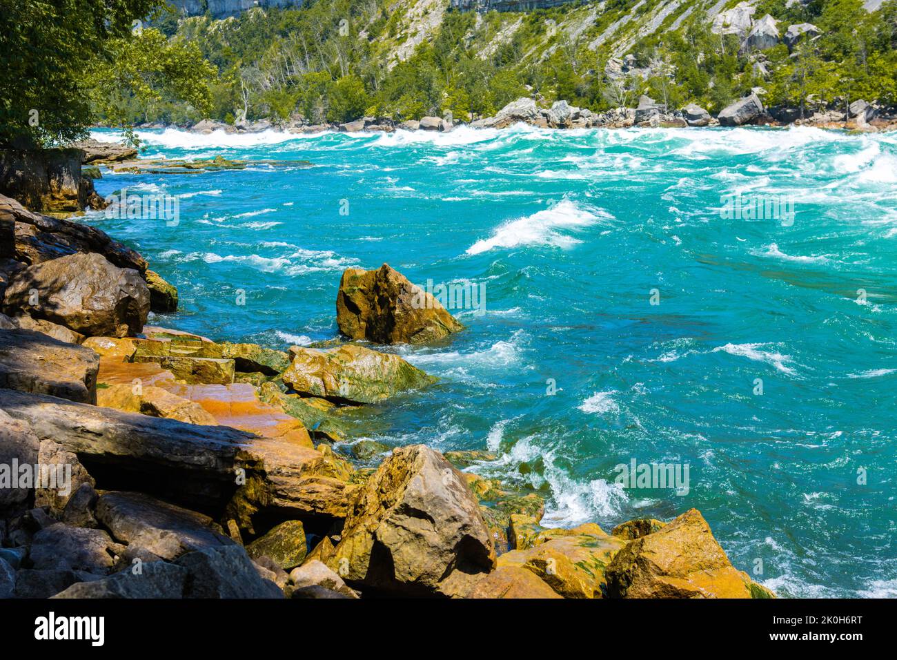 A scenic view of a blue crystal clear river with rocky shores in the ...